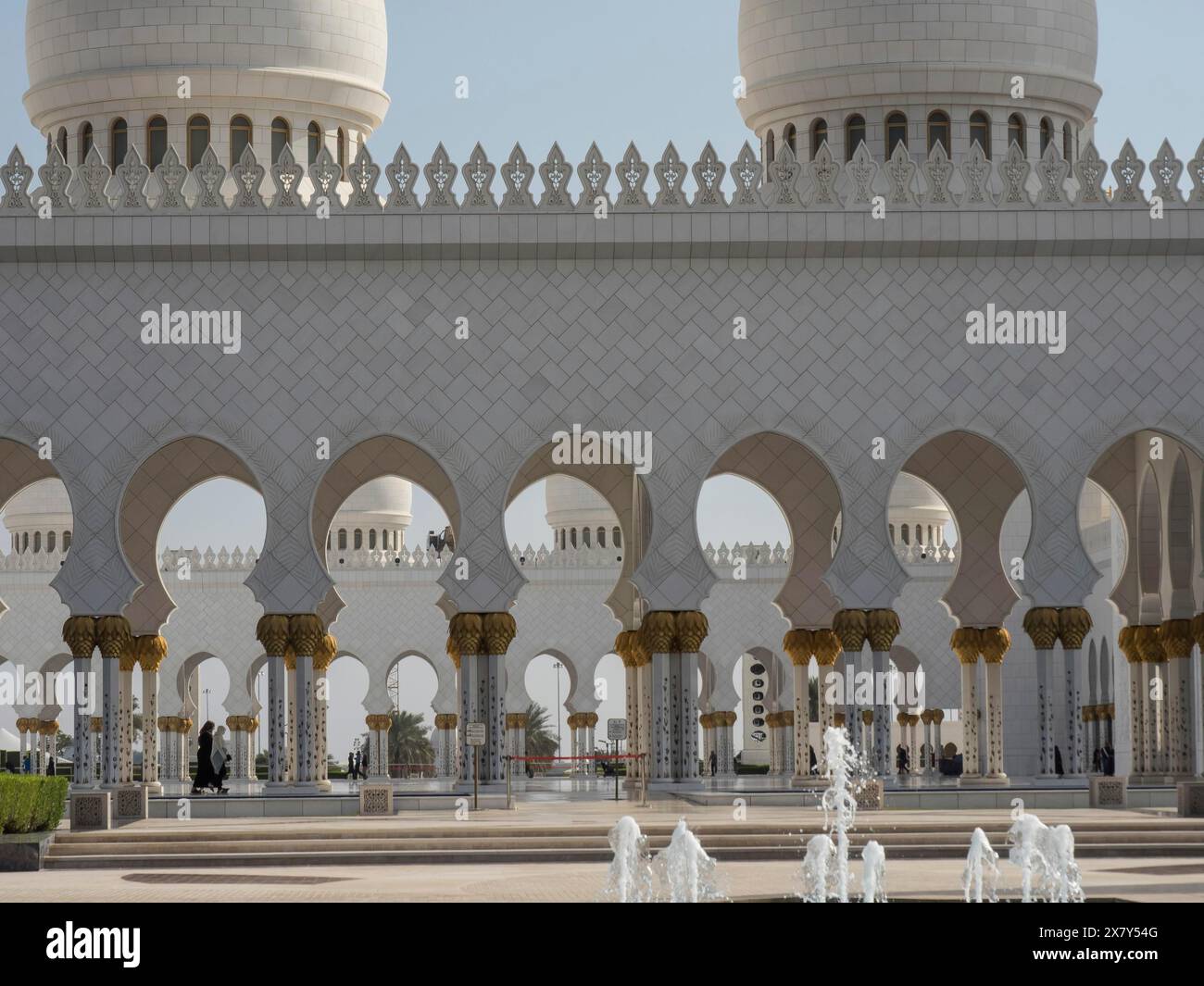 Mosque with arches and ornately decorated columns under a clear sky and ...