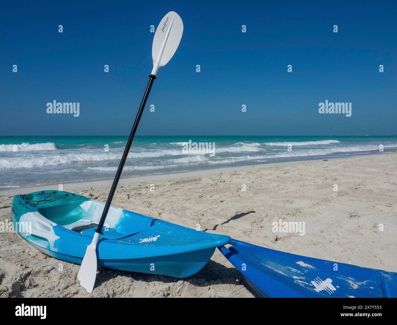 Two kayaks and a paddle in the sand on a beach with clear turquoise ...