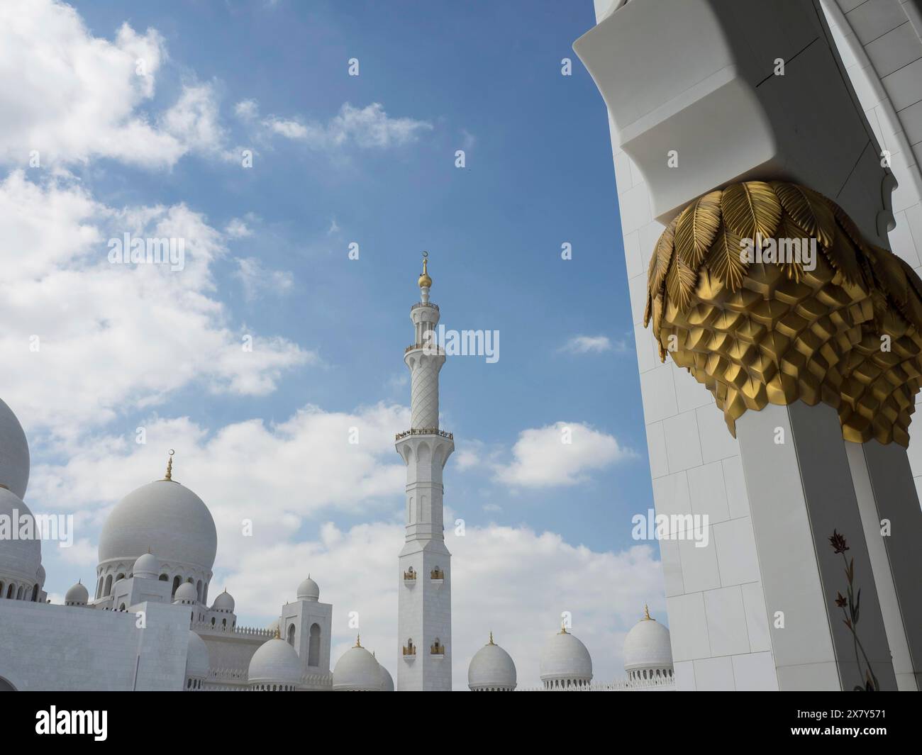 Mosque with a gold decorated detail and a high minaret under a slightly ...
