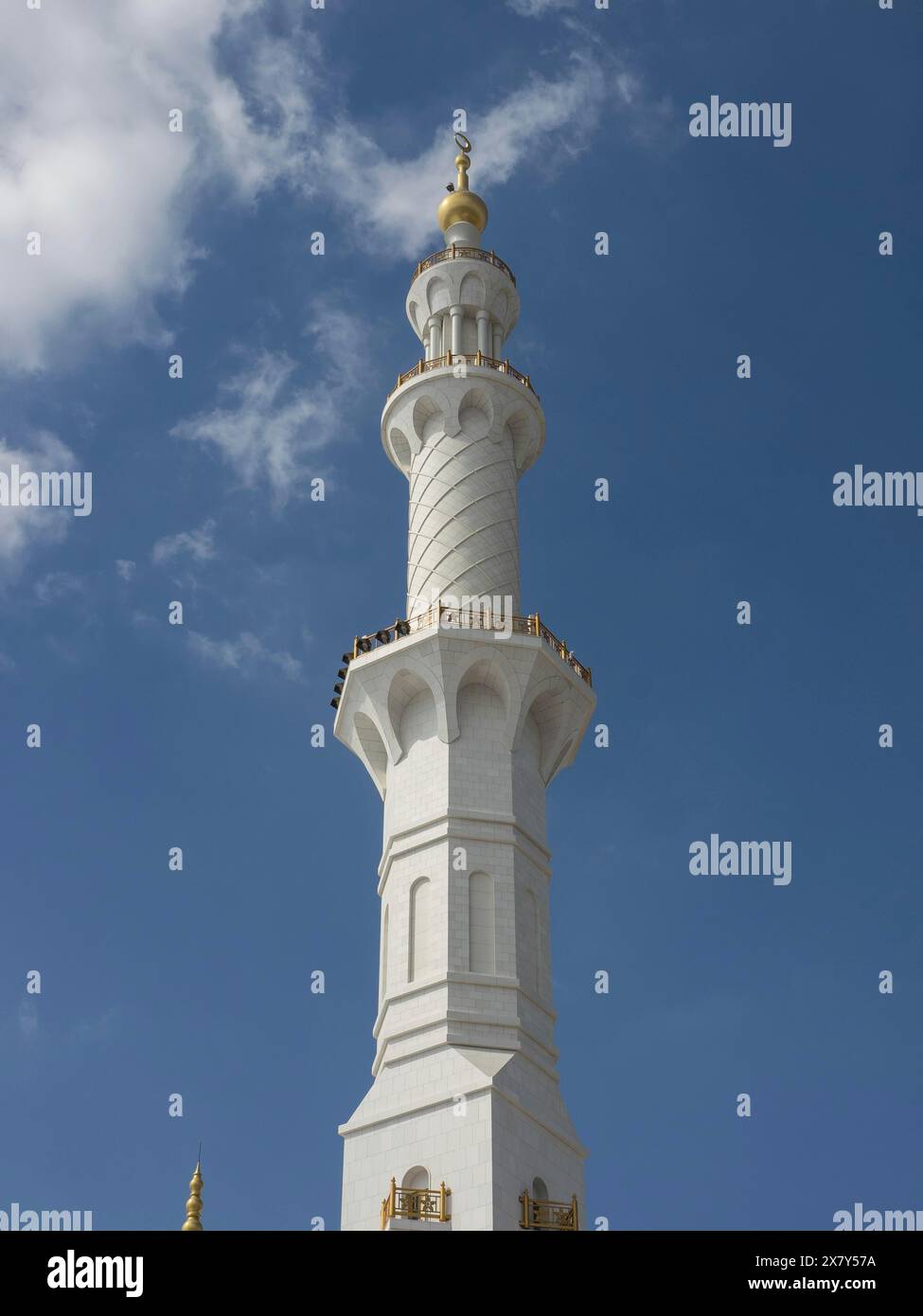 Tall, narrow minaret tower against a clear blue sky, white mosque with ...