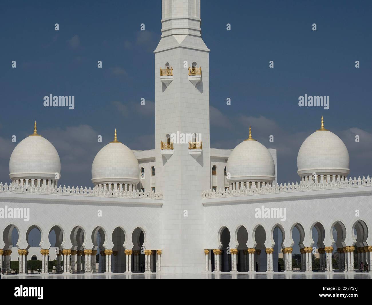 Impressive mosque with white domes and golden decorations under a clear ...