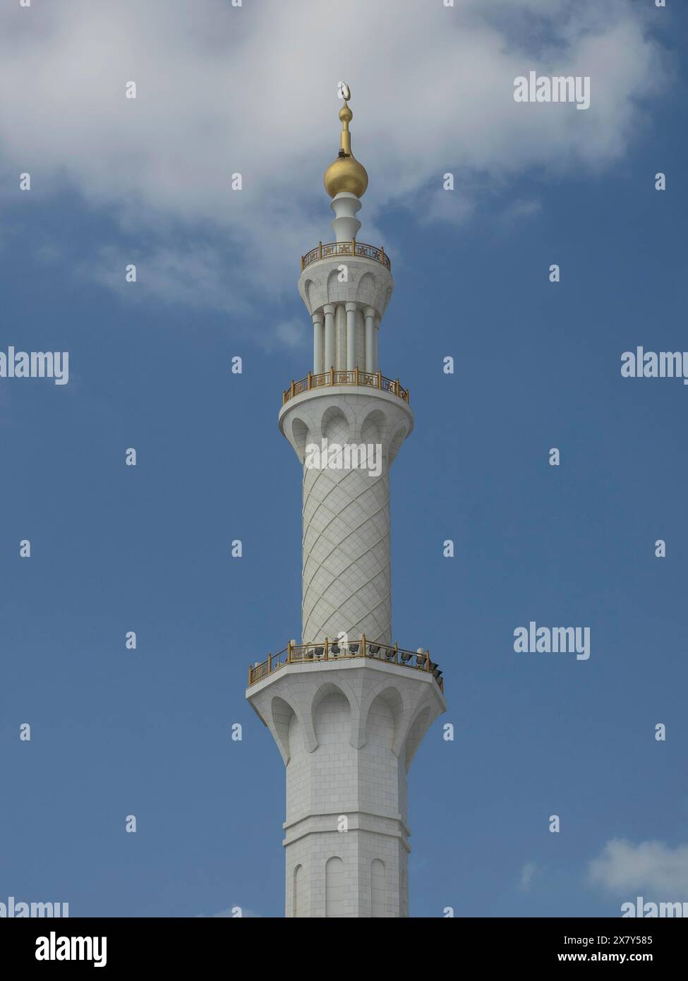 Detailed view of a minaret with a golden spire under a cloudy sky ...