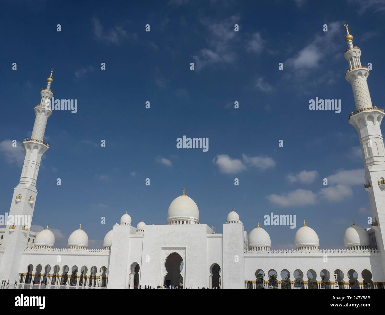 Large mosque with white domes, minarets and golden decorations under a ...