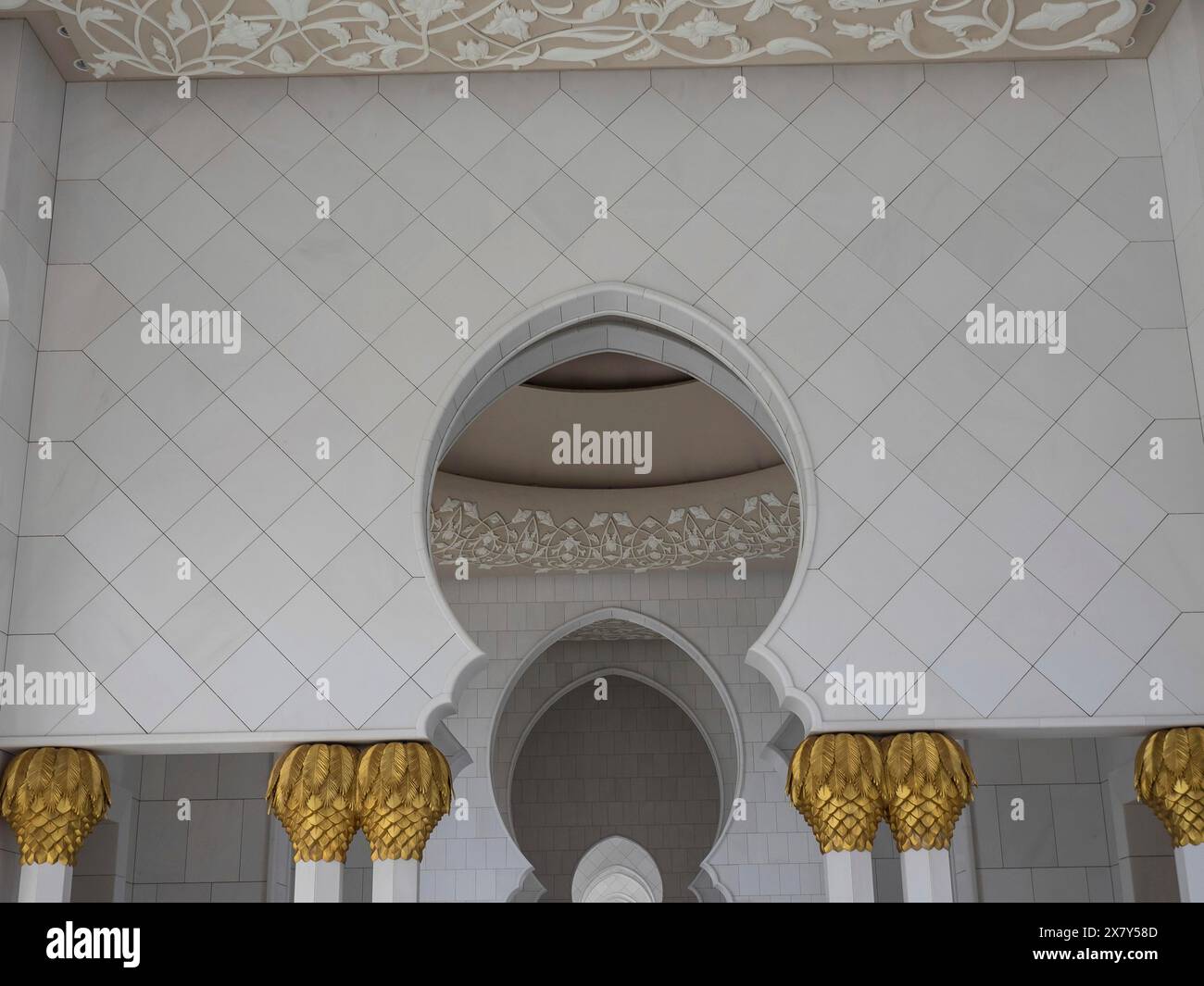 An interior with curved arches and golden decorations, white mosque ...