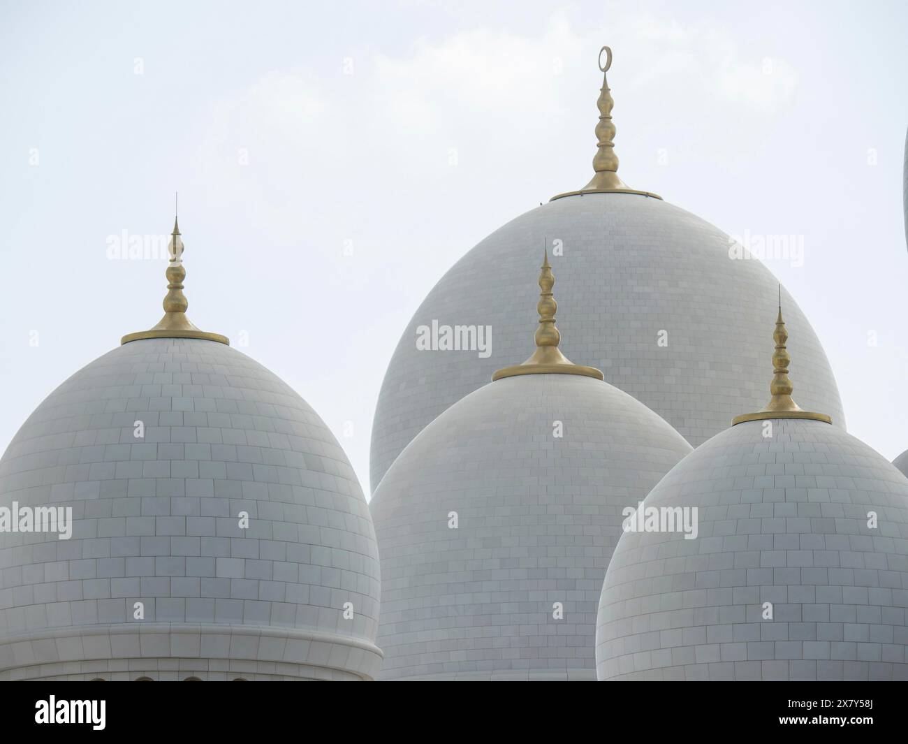 Large white domes of a mosque with golden spires against a sunny sky ...