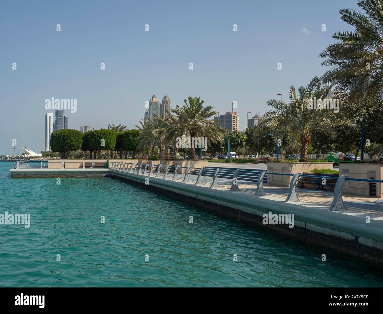 A relaxed waterfront promenade with views of water, skyscrapers and ...