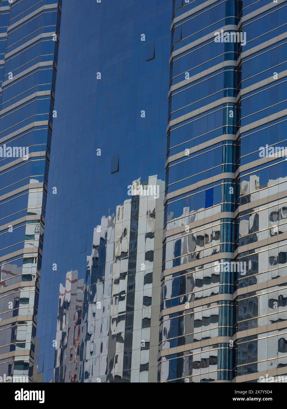 Two modern high-rise buildings with glass facades reflecting other ...