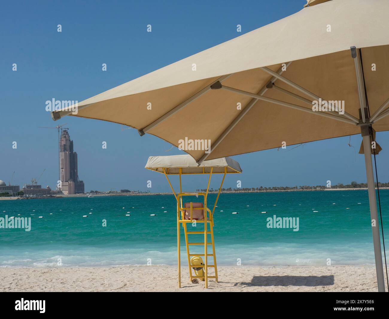 Yellow lifeguard chair and parasol on the beach with turquoise water ...