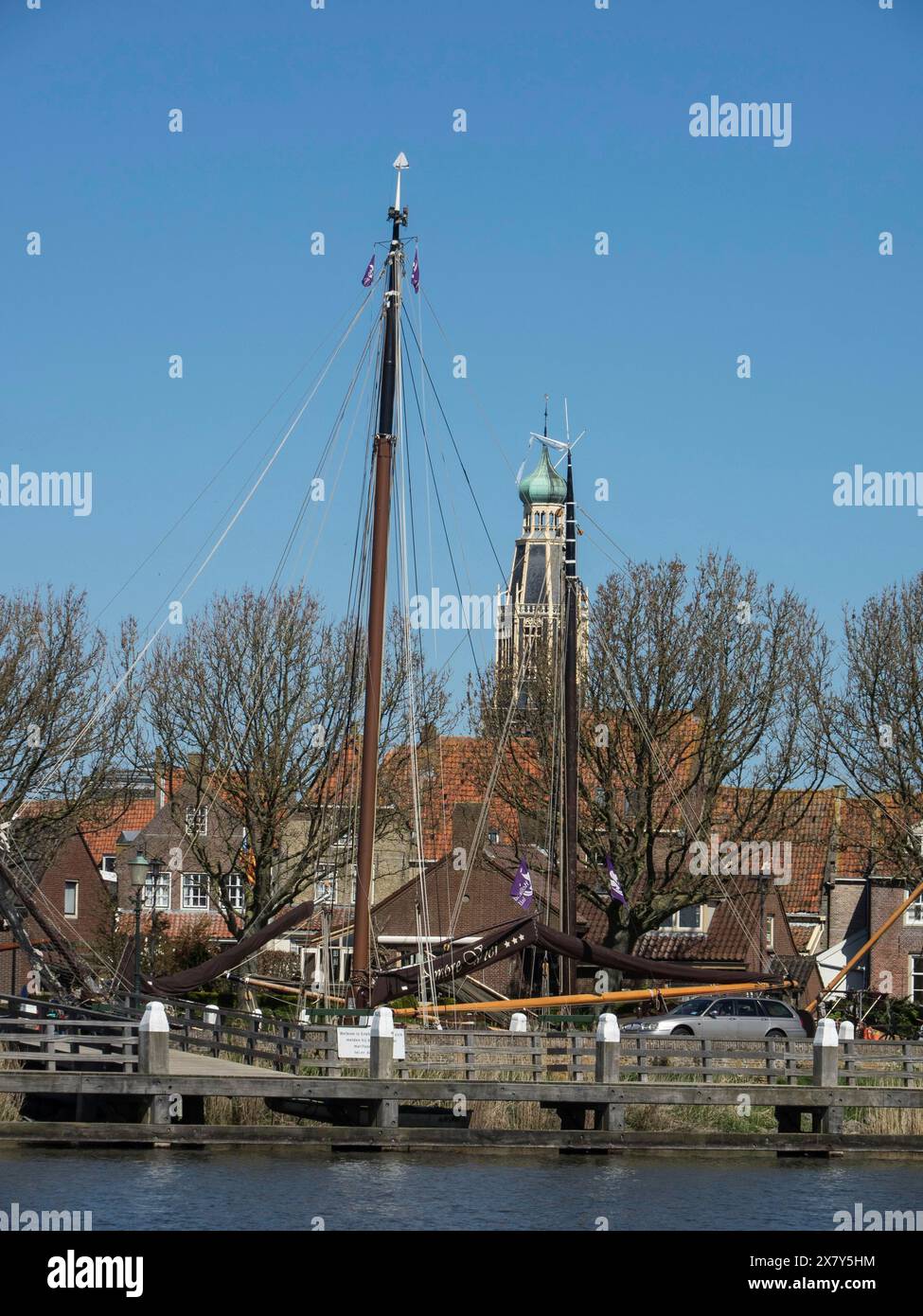 Sailing ship with towering masts, red houses and a striking tower under ...