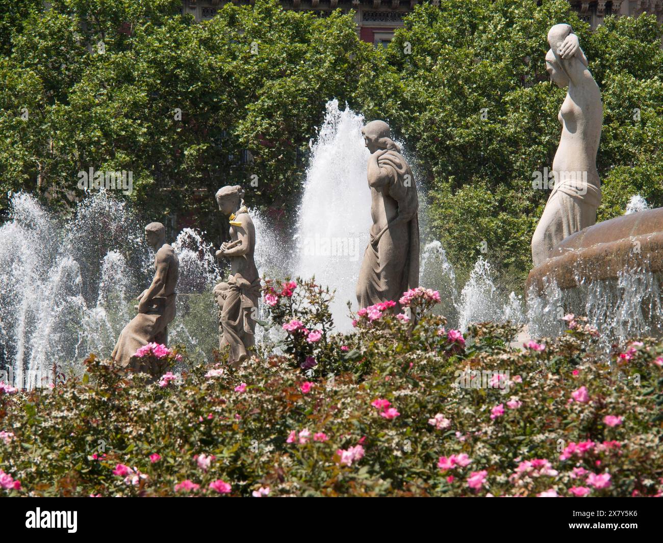 Close-up of a fountain with statues, surrounded by blooming flowers and ...