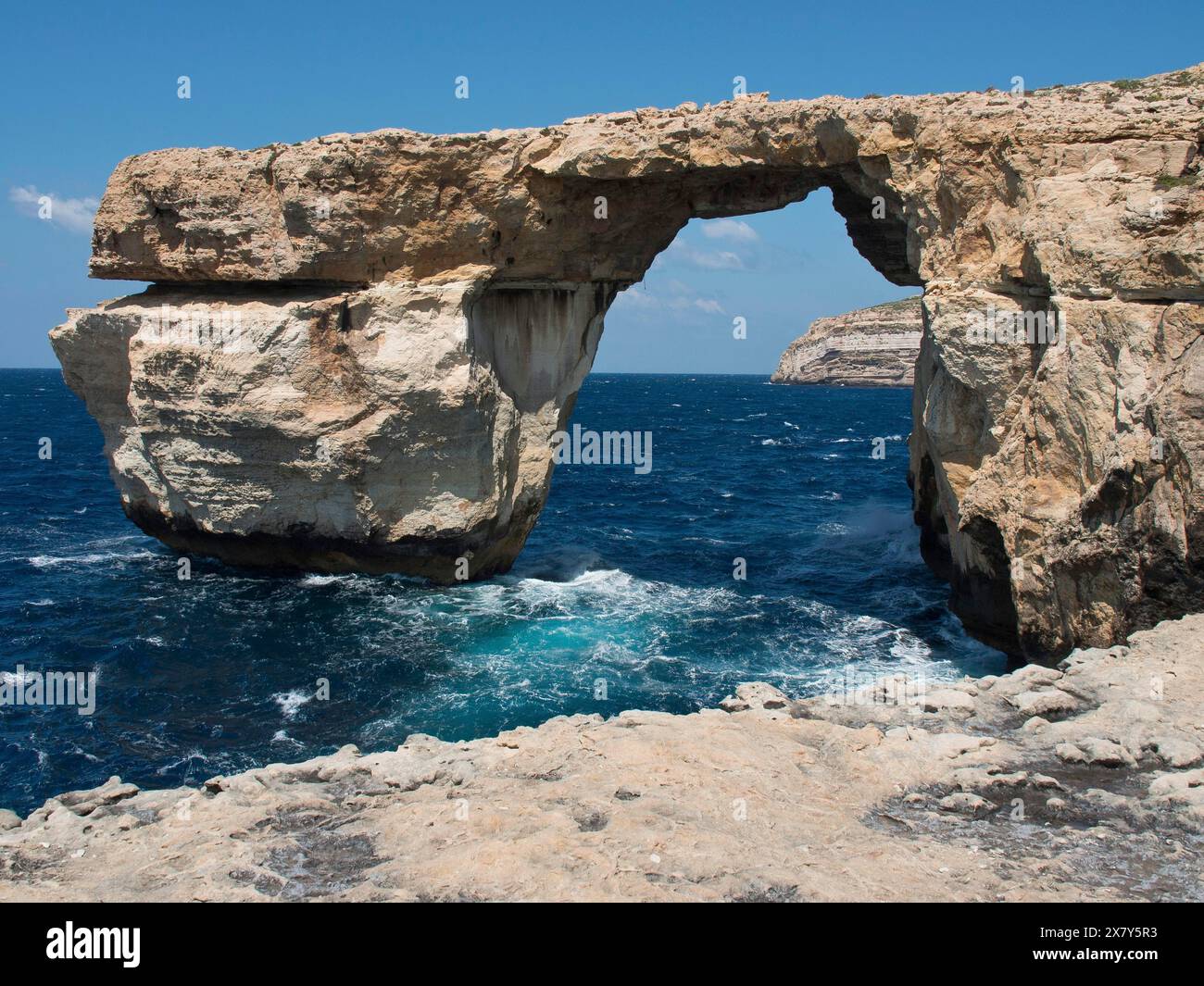 Natural rock arch stretches over the sea, surrounded by coastal cliffs ...