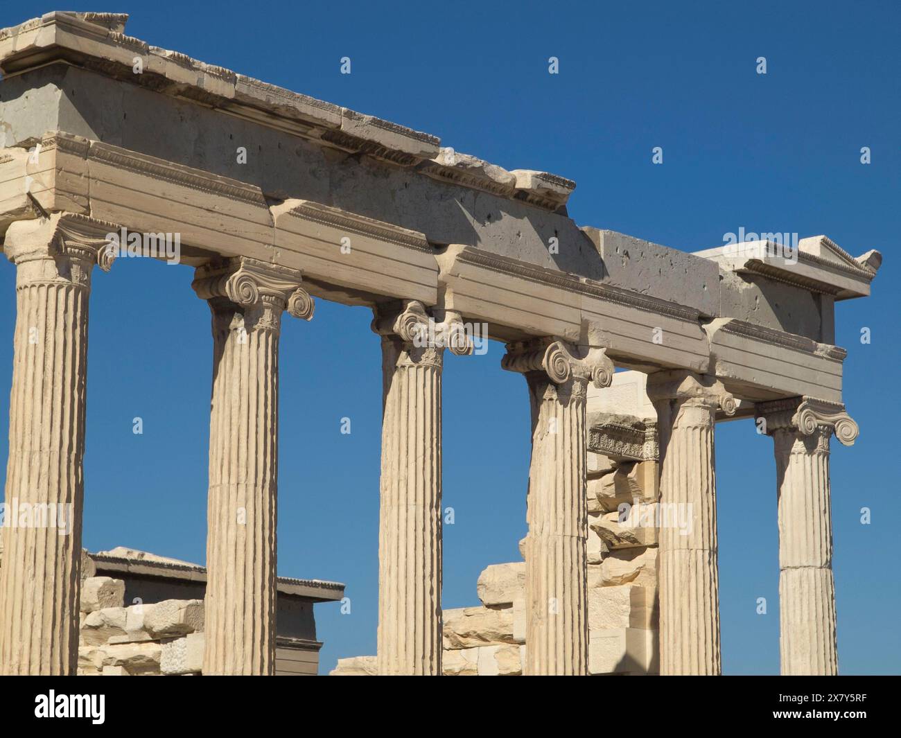Ancient Greek ruins with columned facade under clear blue sky, historic columns and ruins at an ...