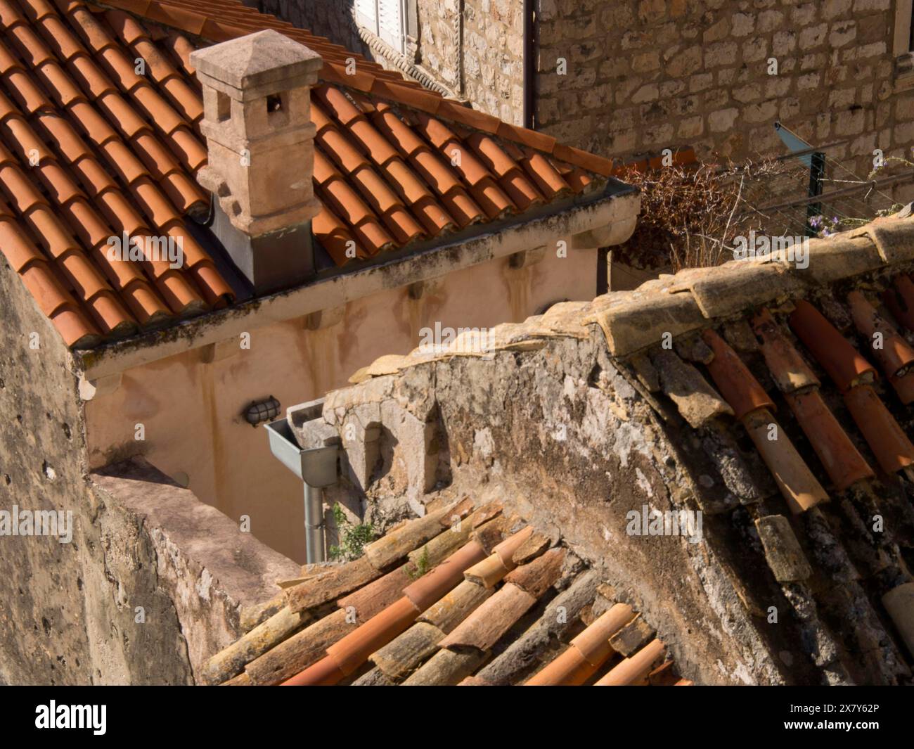 Close-up of rustic rooftops with stone walls and a chimney ...