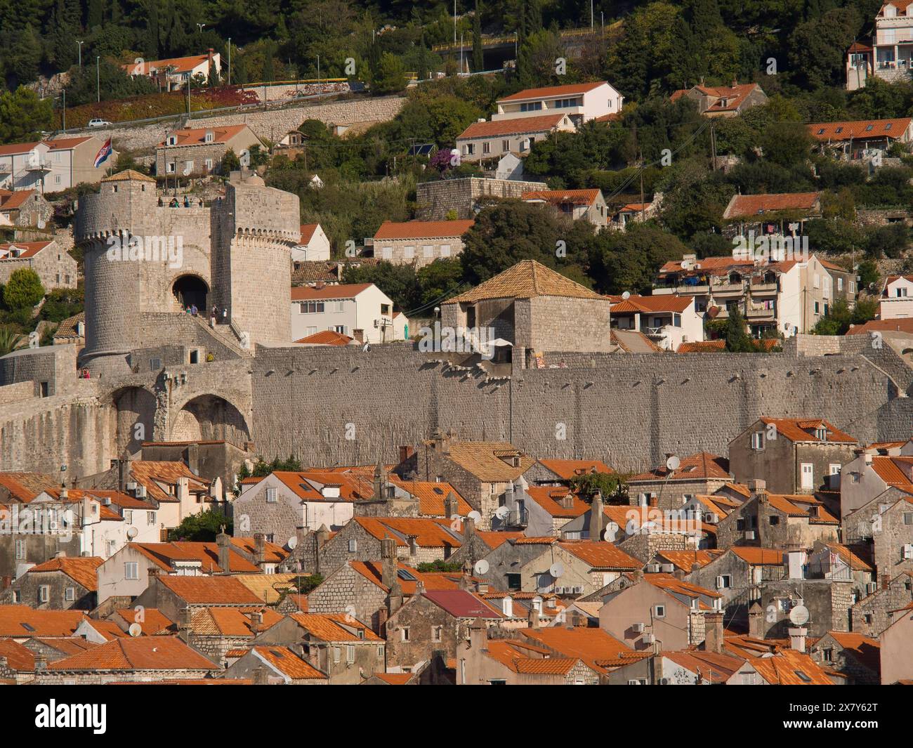 Castle with stone walls overlooking a town with red-tiled rooftops ...