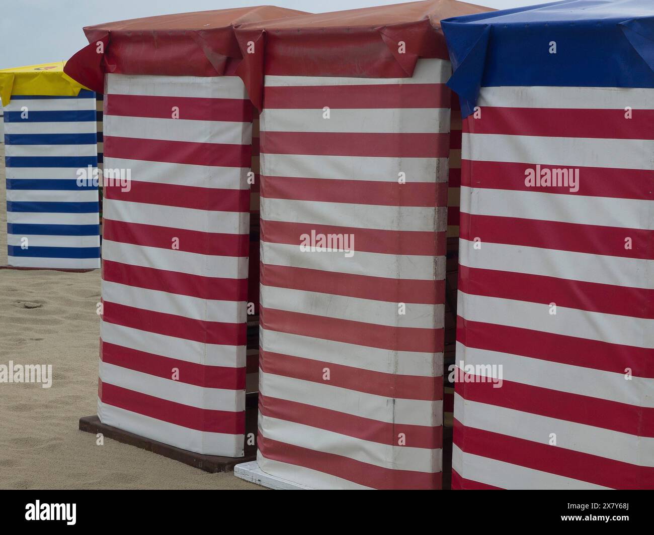 Striped beach huts in red-white and blue-white on the sandy beach ...