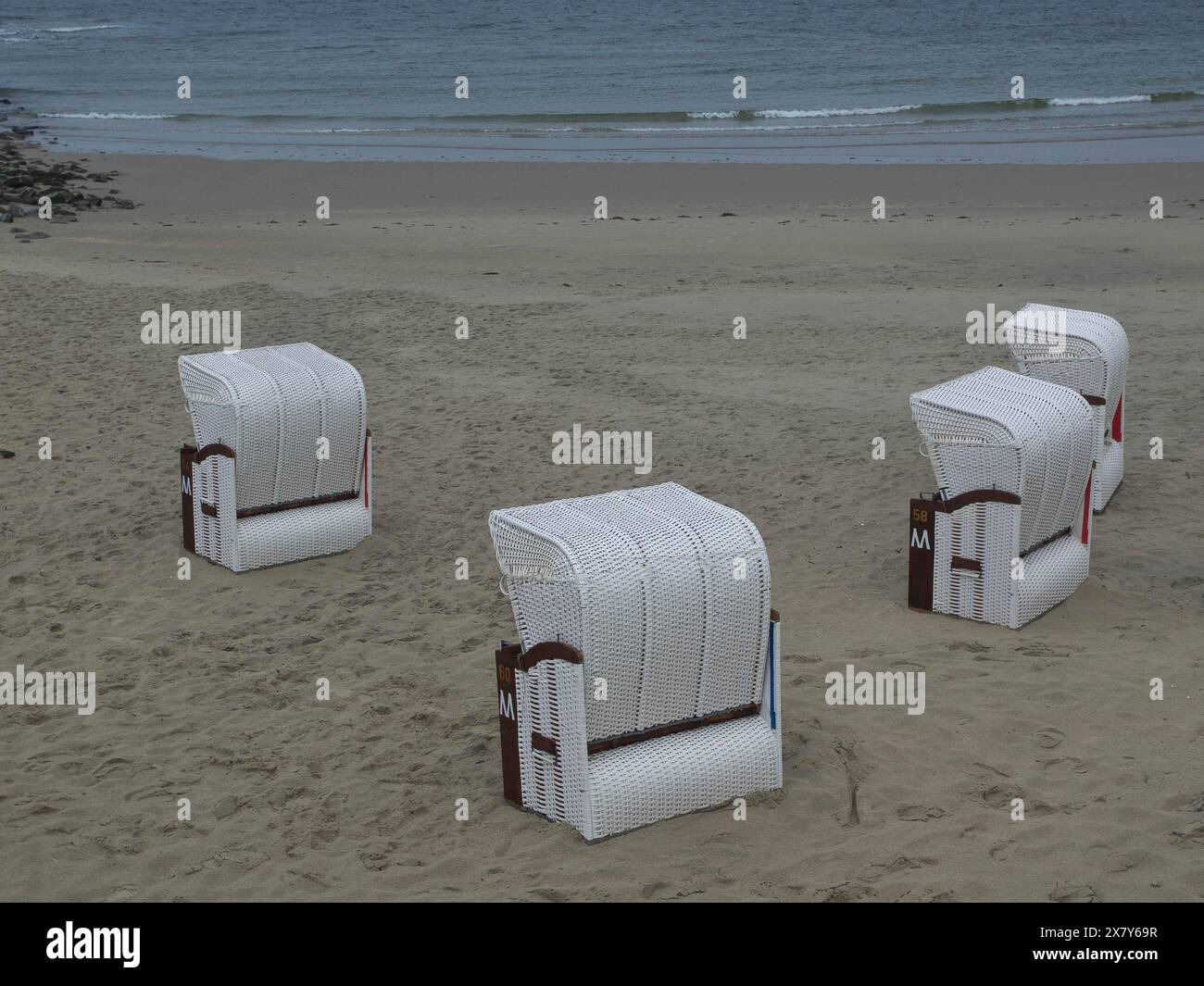 Four white beach chairs on an empty beach with calm sea in the ...