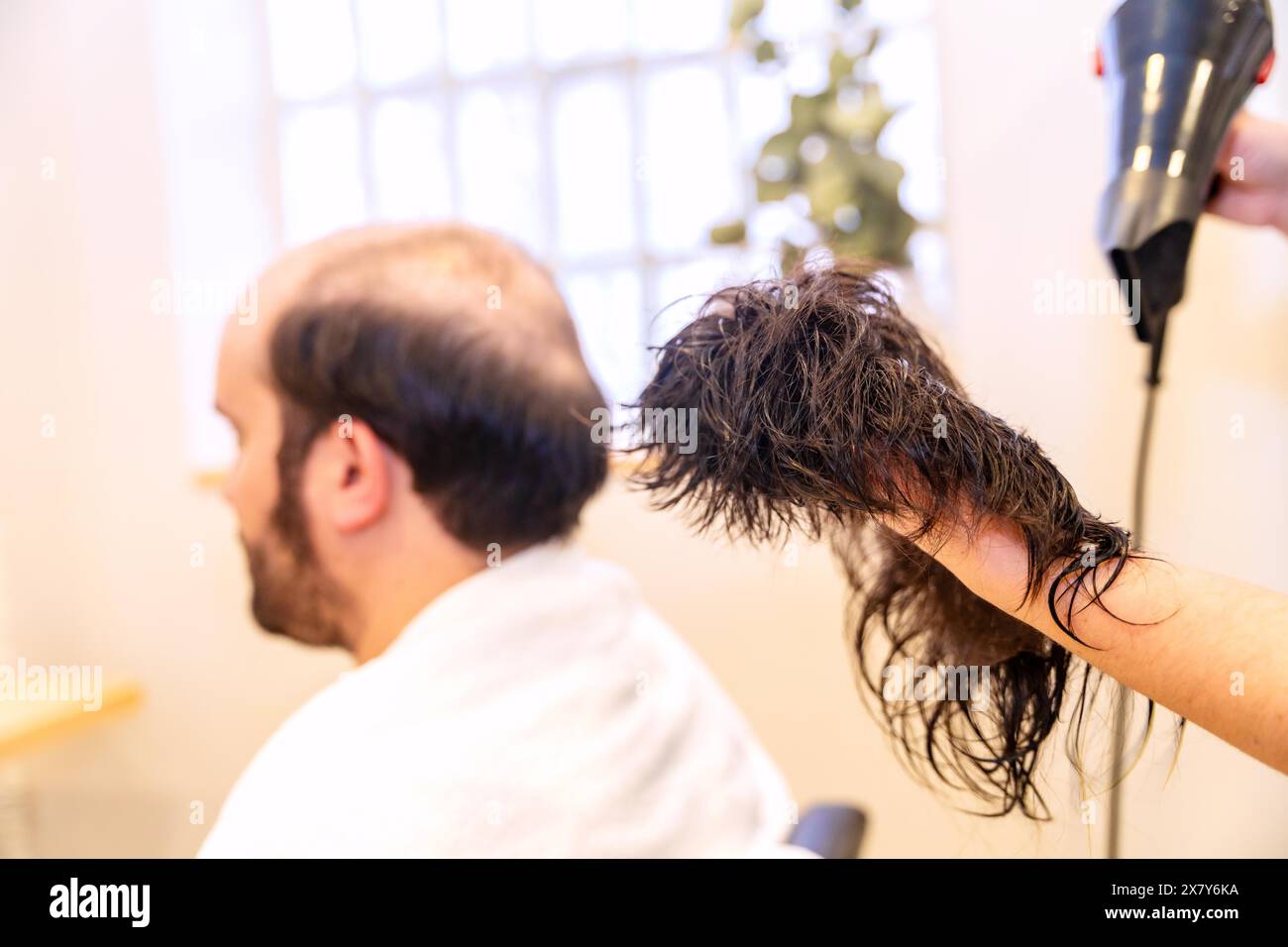 Bald man waiting while hairdresser cleaning and drying his capillary ...