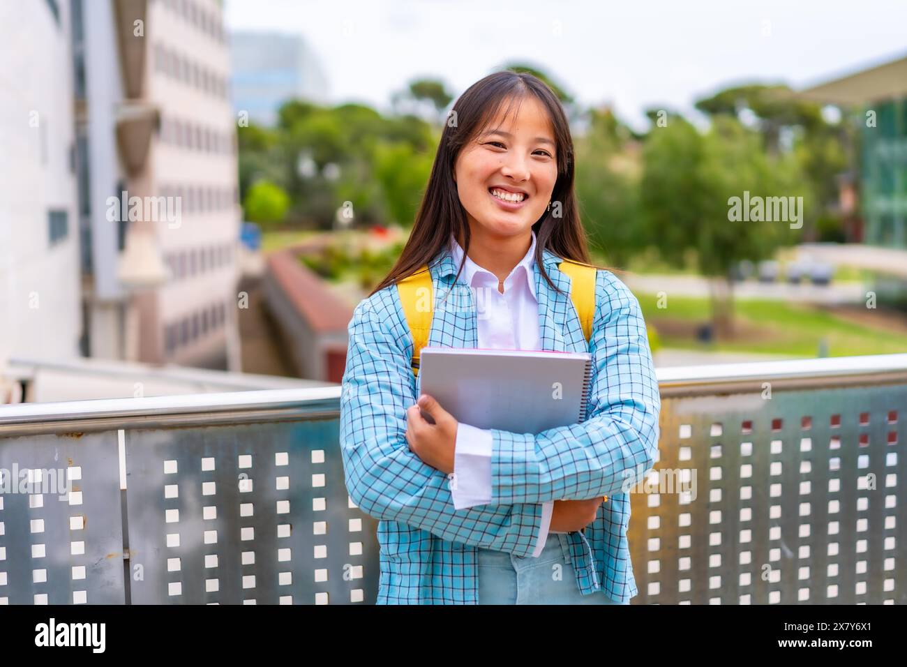 Cute chinese university student smiling at camera standing outdoors in ...