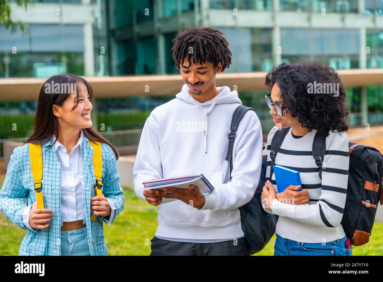 Happy multi-ethnic university students reading notes together standing ...