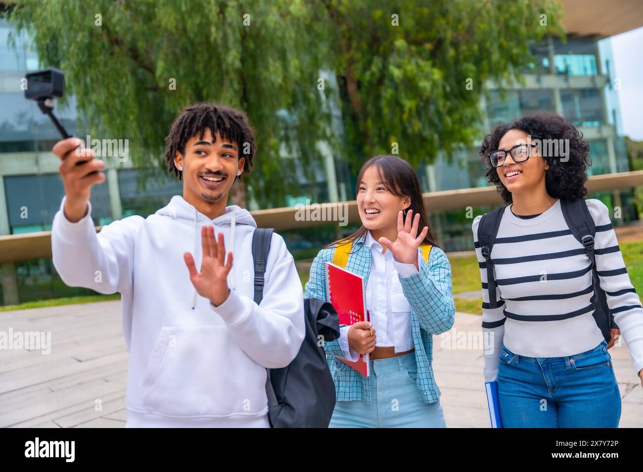 Three multi-ethnic students waving during video call outside the ...