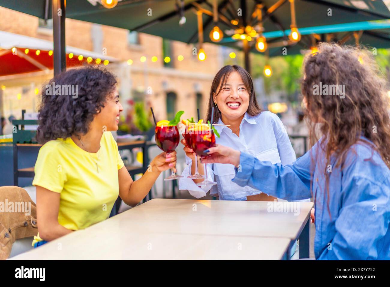 Three multi-ethnic female friends enjoying celebrating toasting with ...