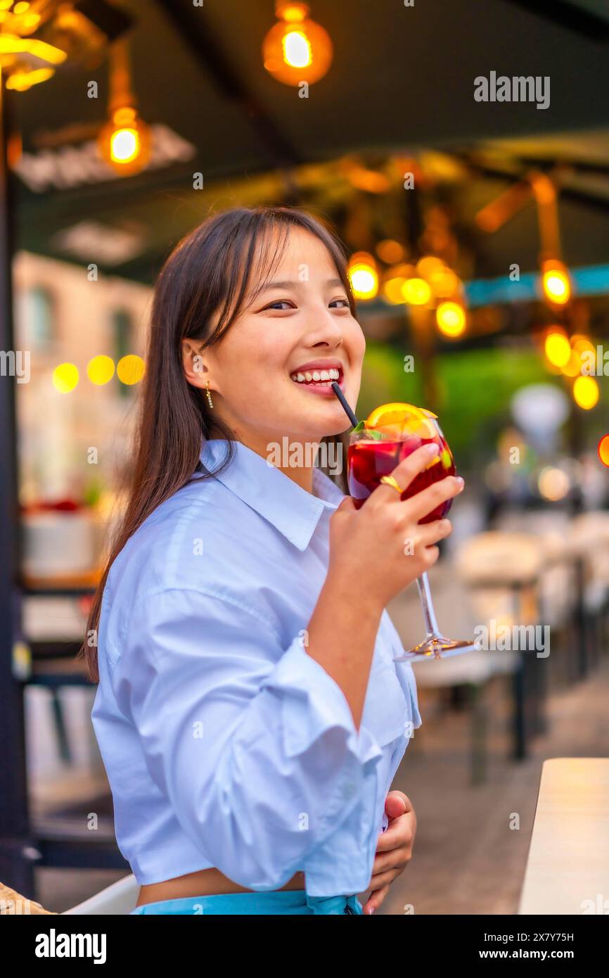 Vertical portrait of a chinese woman drinking tropical cocktail using ...