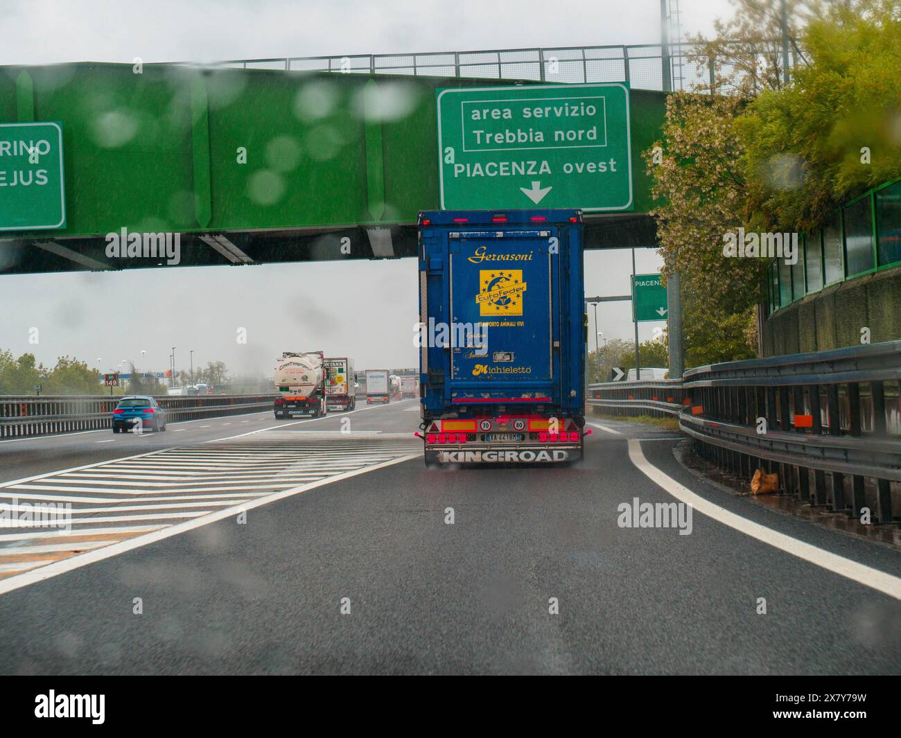 A stretch of highway with trucks traveling in the rain, under an ...