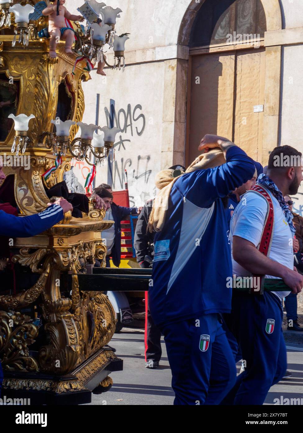 An ornate statue carried by people during a religious procession on a ...