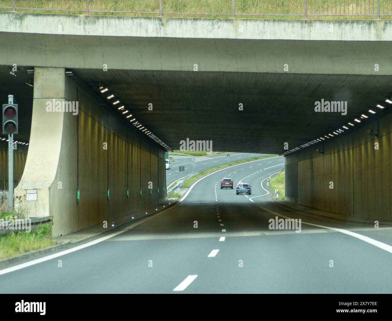 A highway with a tunnel in the middle. The tunnel is dark and the cars ...
