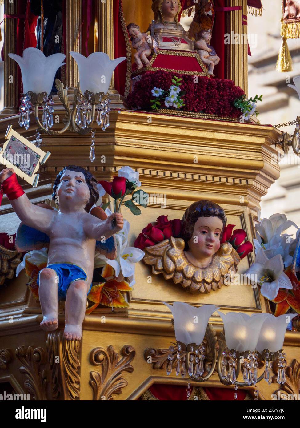 A detailed gold float with a cherub and flowers as part of a religious ...