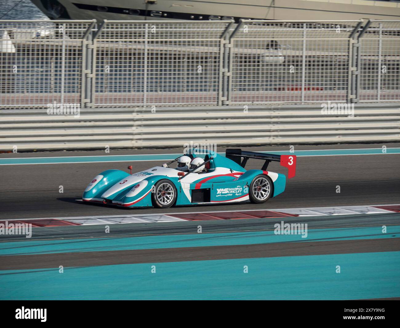 A racing car at full speed on a winding track, tarmac glistening under ...