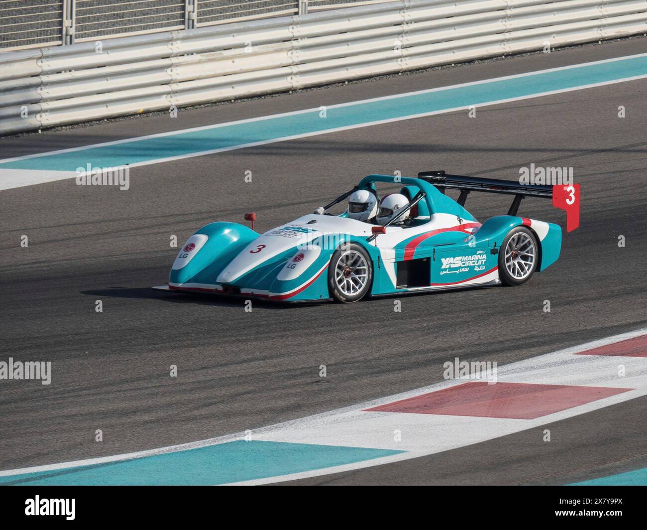 A racing car drives at high speed on a race track surrounded by safety ...