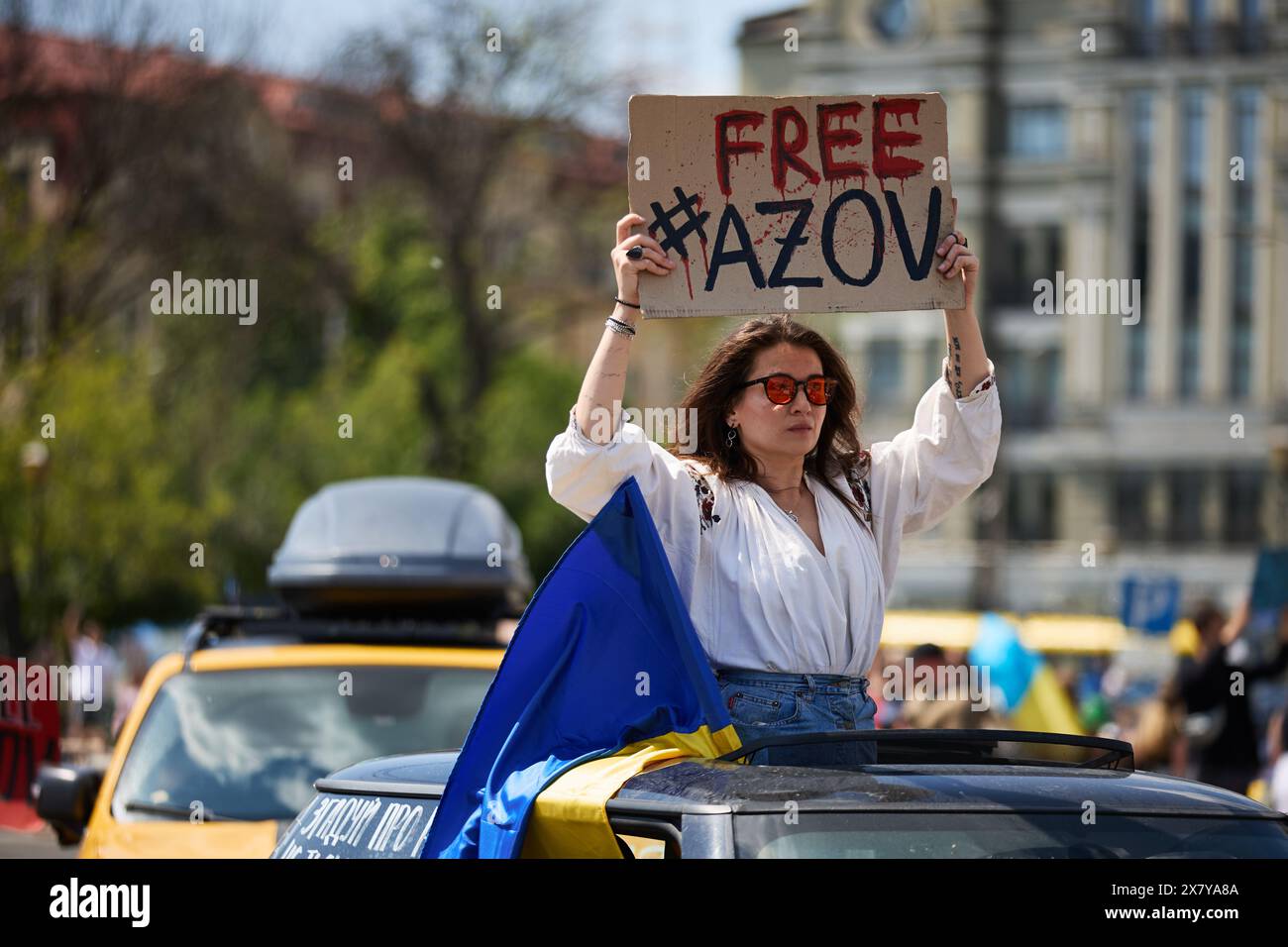 Ukrainian woman demonstrating a sign "Free Azov" out of a car window ...