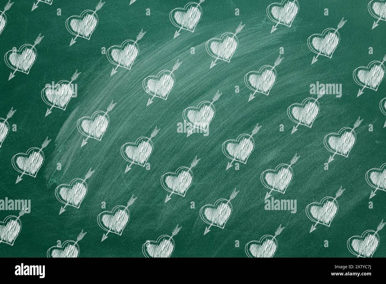 A green classroom chalkboard displays a whimsical pattern of hearts ...