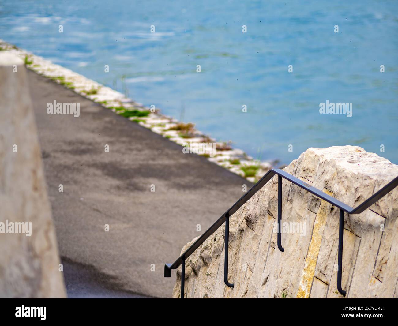 A serene waterside path alongside calm blue Rhine river in Basel ...