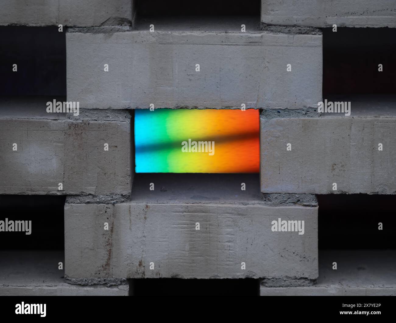 A close-up of grey concrete bricks with a rainbow light gap, creating ...