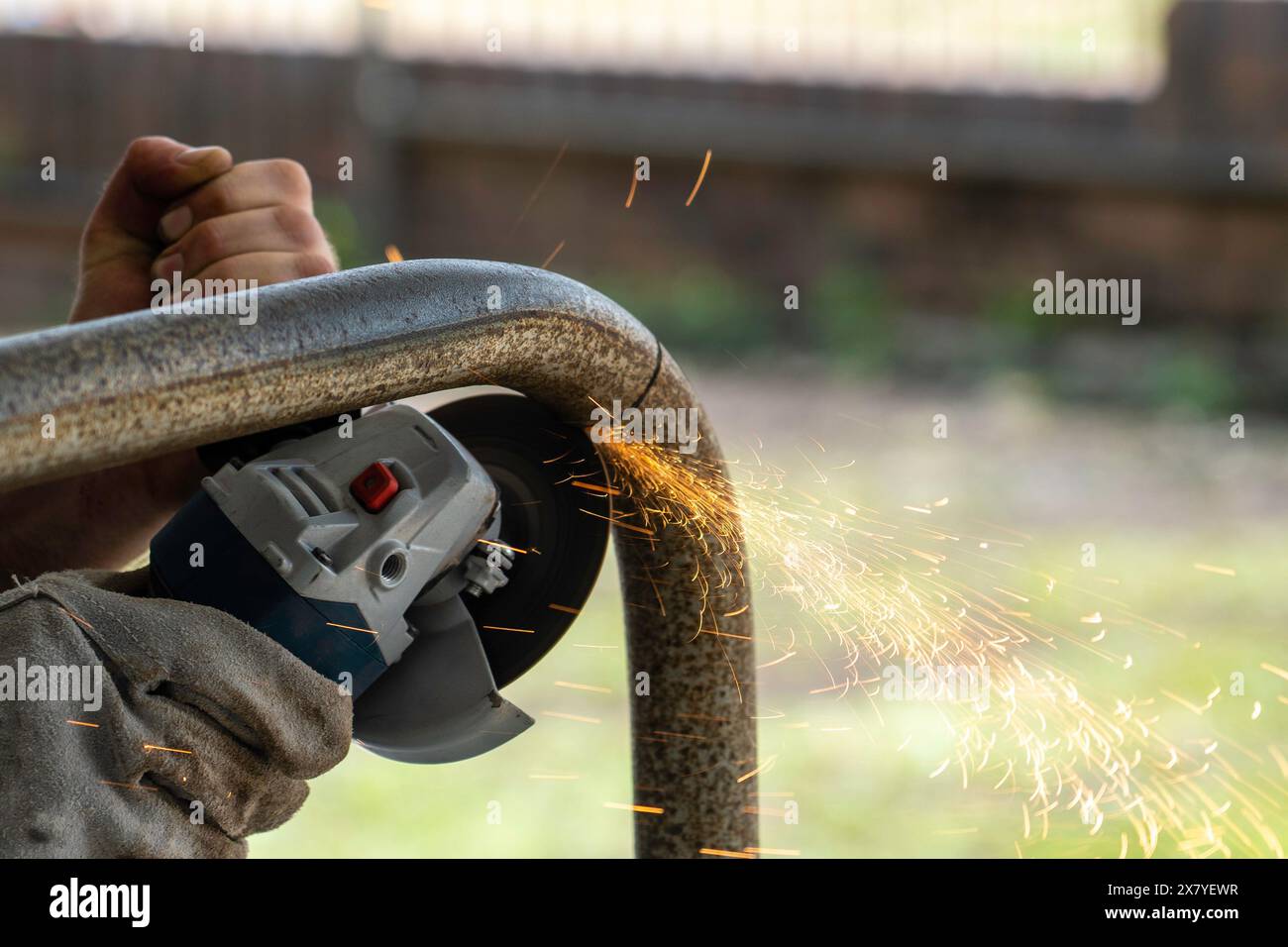 Closeup of a person with a angle grinder, cutting a pole out of the ...