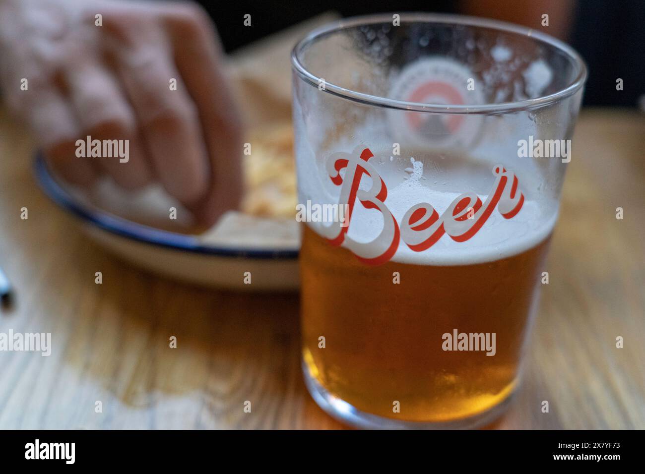 Close up of a persons hand with beer and hot chips in a pub Stock Photo ...