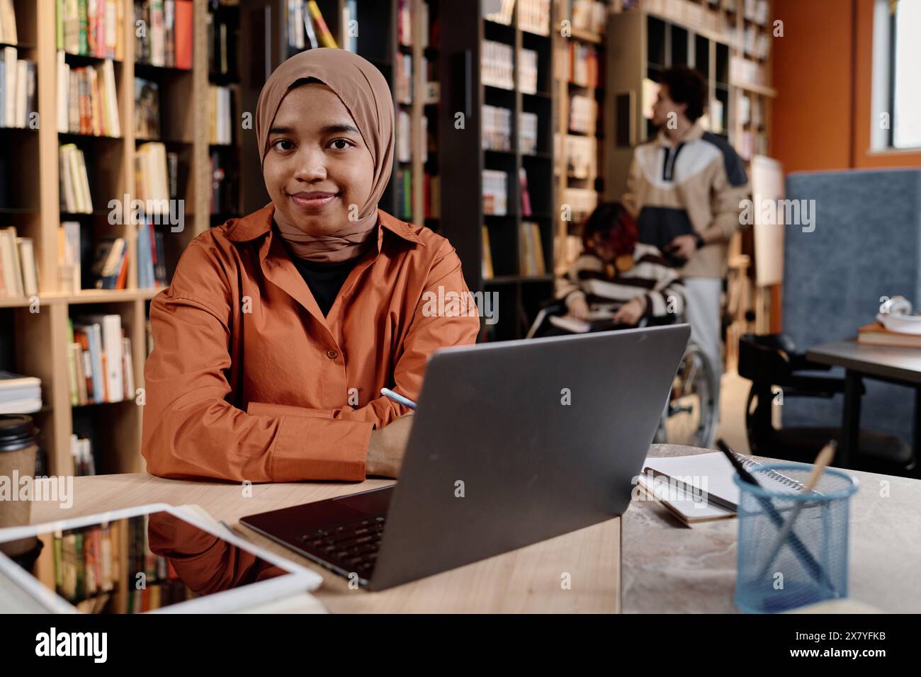 Modern Muslim girl wearing hijab sitting at desk in college library ...