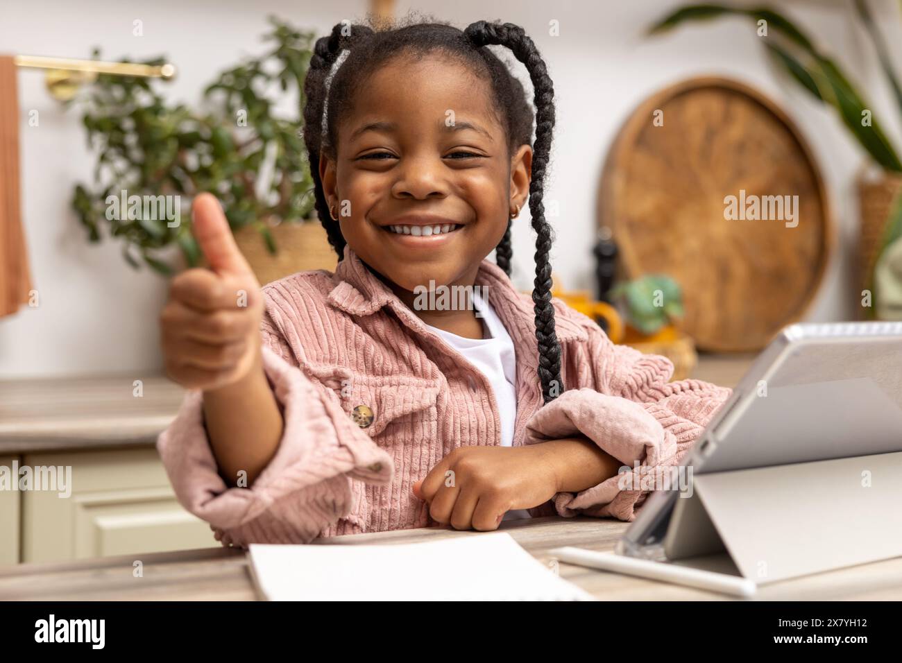 Child siting at table completing her schoolwork with the help of her ...