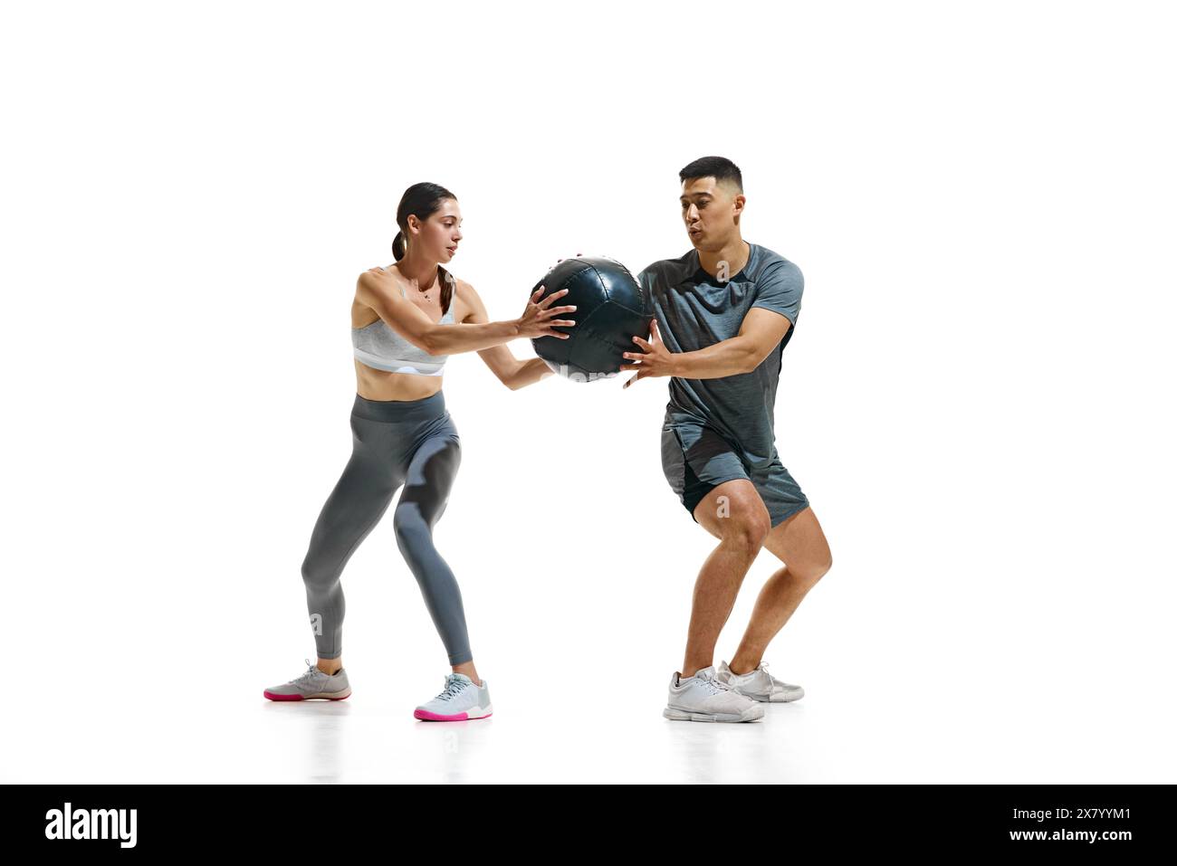 Athletic man and a woman performing exercise with heavy medicine ball ...