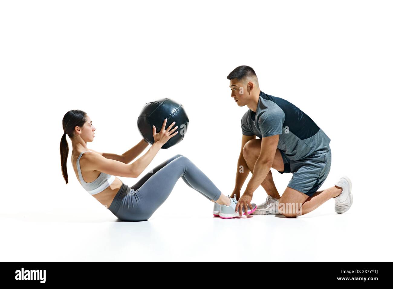 Young woman doing abdominal exercises with medicine ball and her male ...