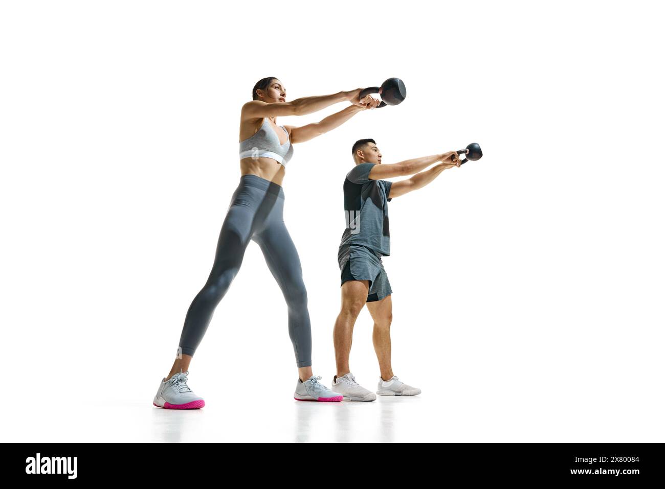 Dynamic portrait of fit man and woman performing kettlebell squat ...