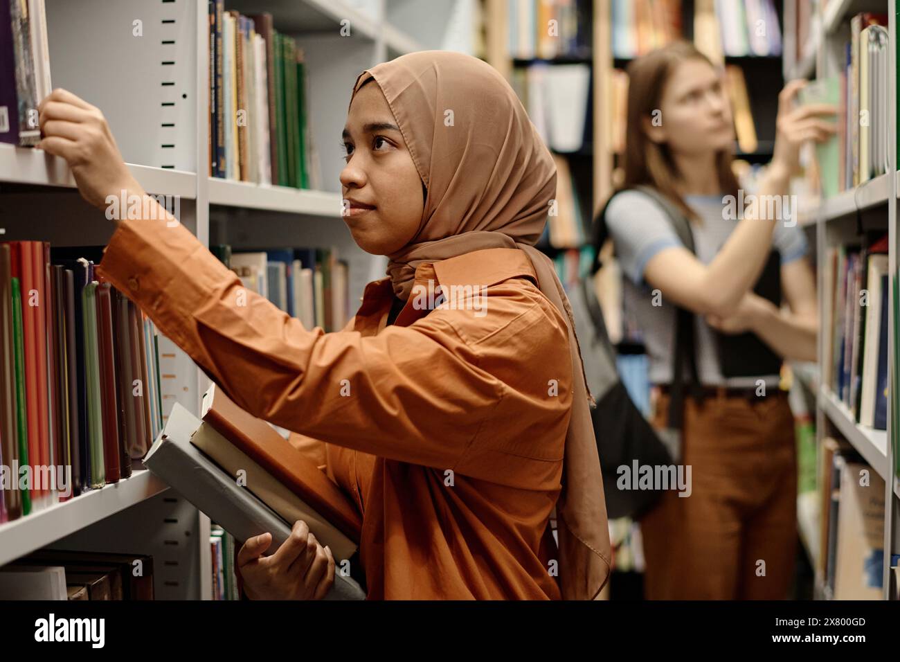 Selective focus shot of biracial female students choosing and taking ...