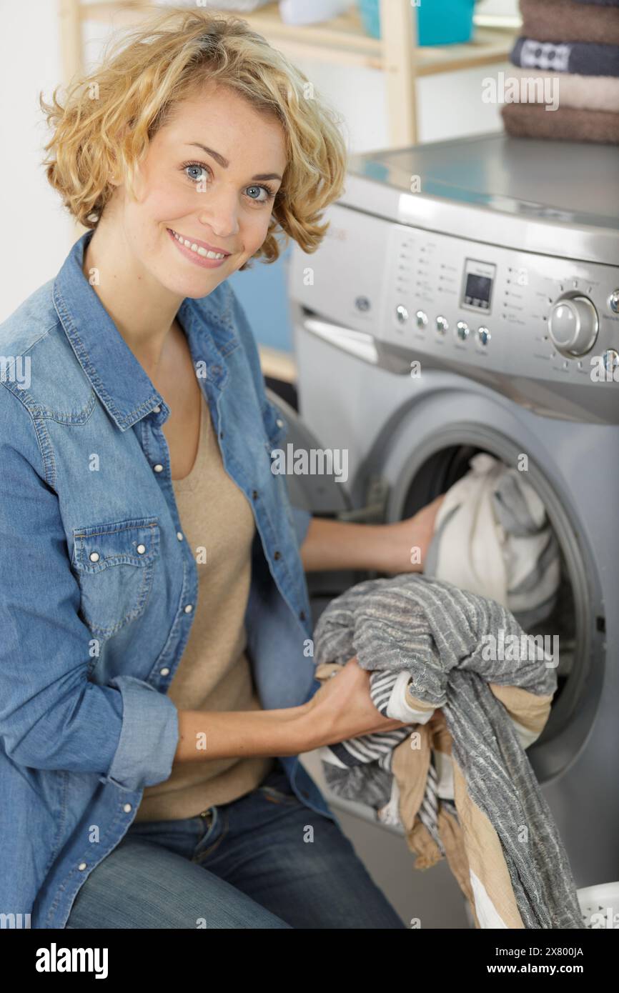 happy woman putting clothes in washing machine for laundry Stock Photo ...