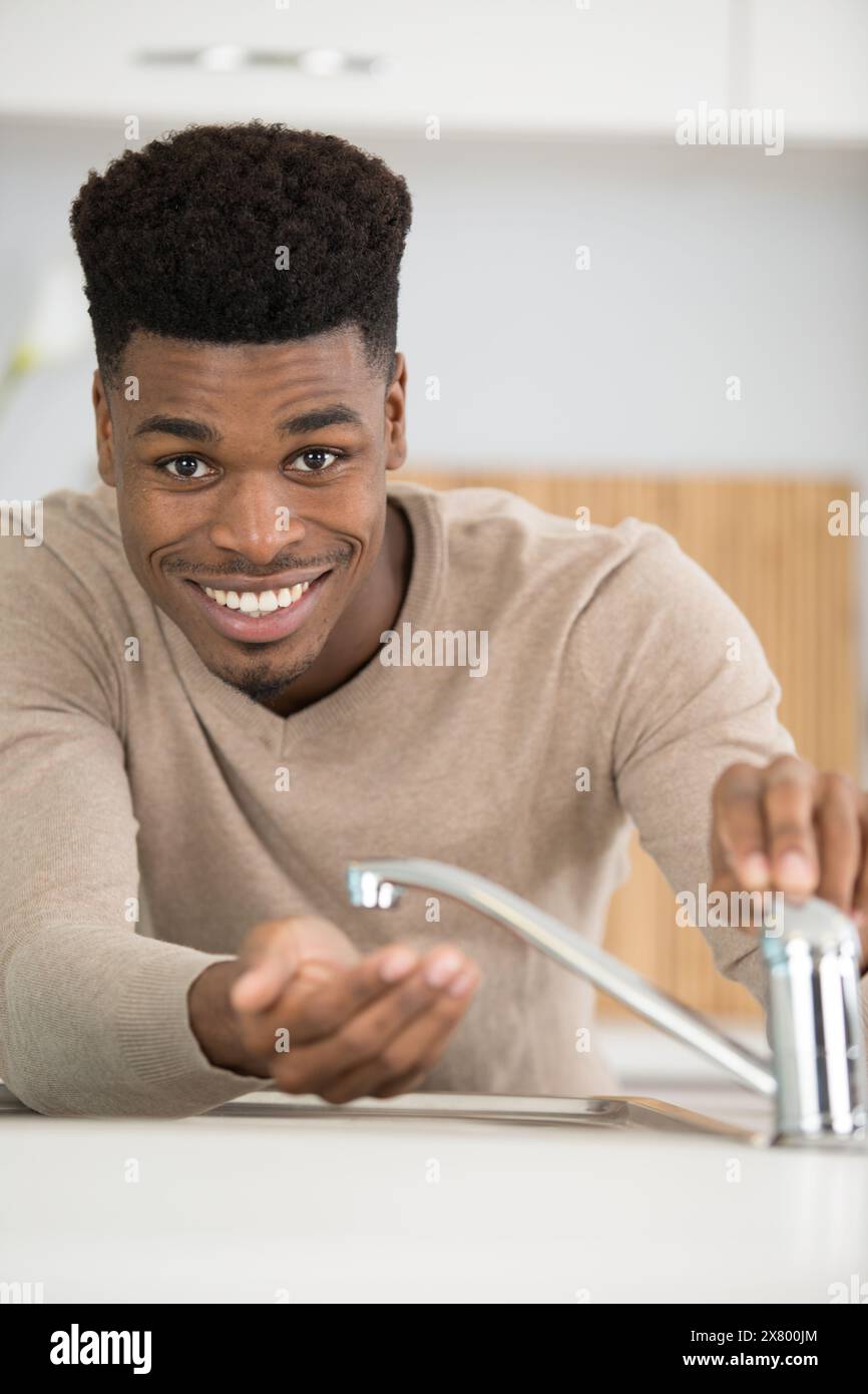 young man opening a tap Stock Photo - Alamy