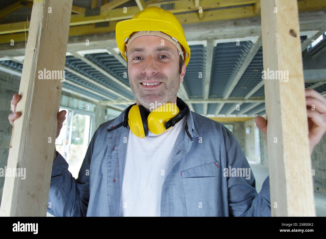 portrait of a builder looking through a wooden door frame Stock Photo ...