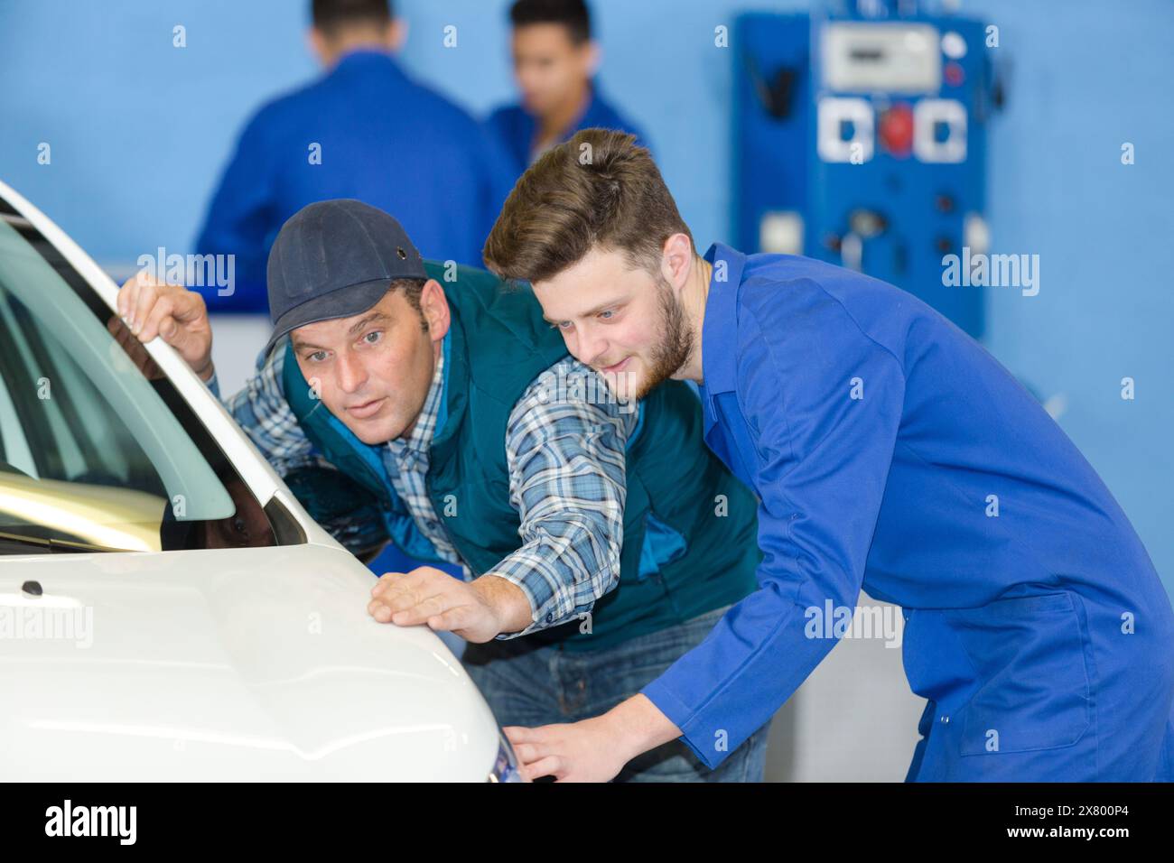 mechanic and trainee working with car Stock Photo - Alamy