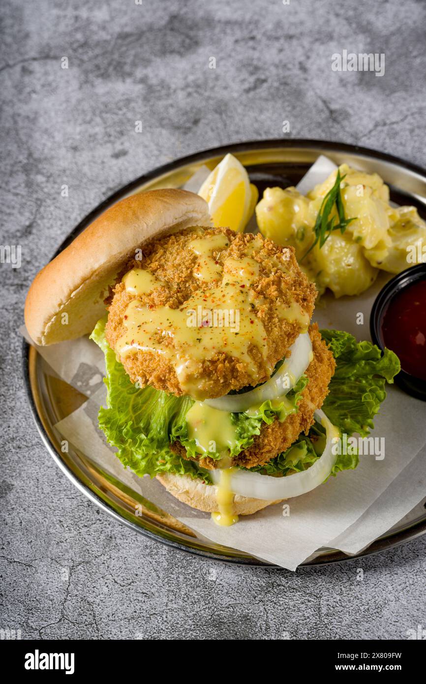 Double fish burger with potato salad on a metal plate Stock Photo - Alamy