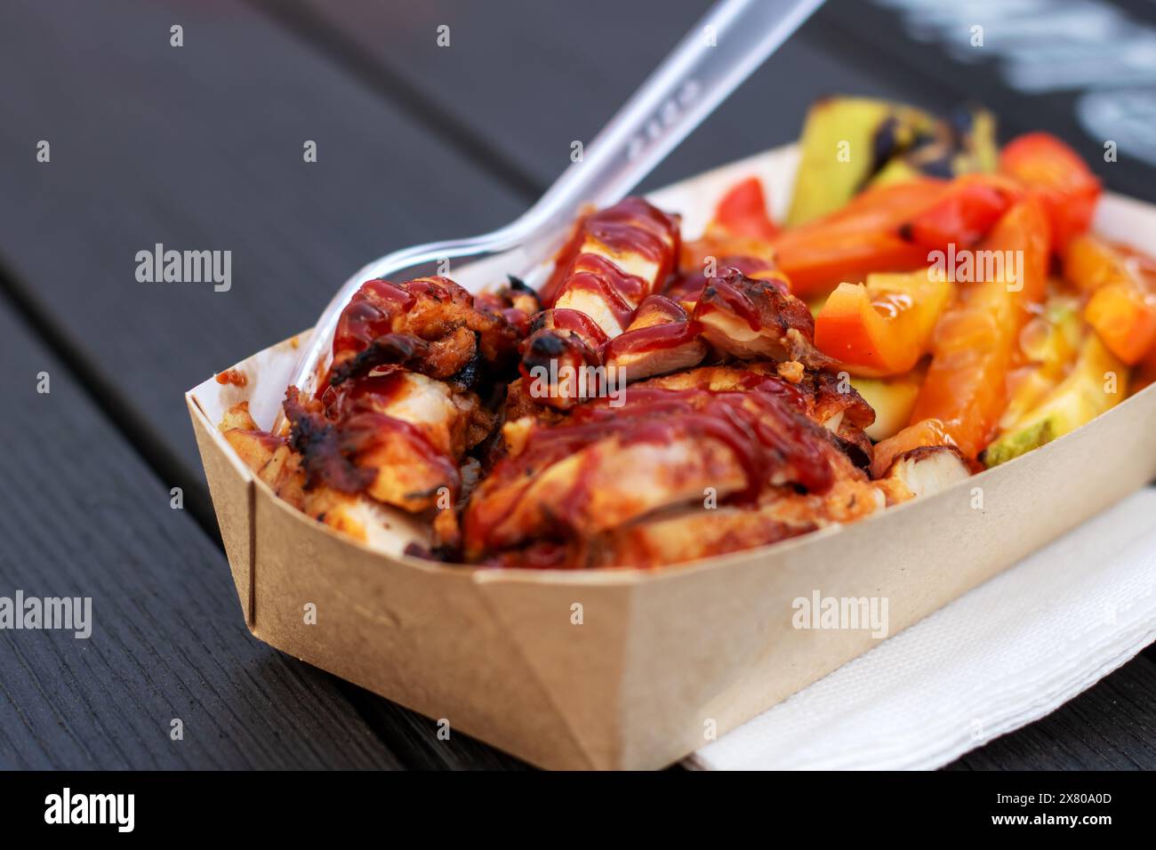 A paper container filled with a Californiastyle pizza topped with ...